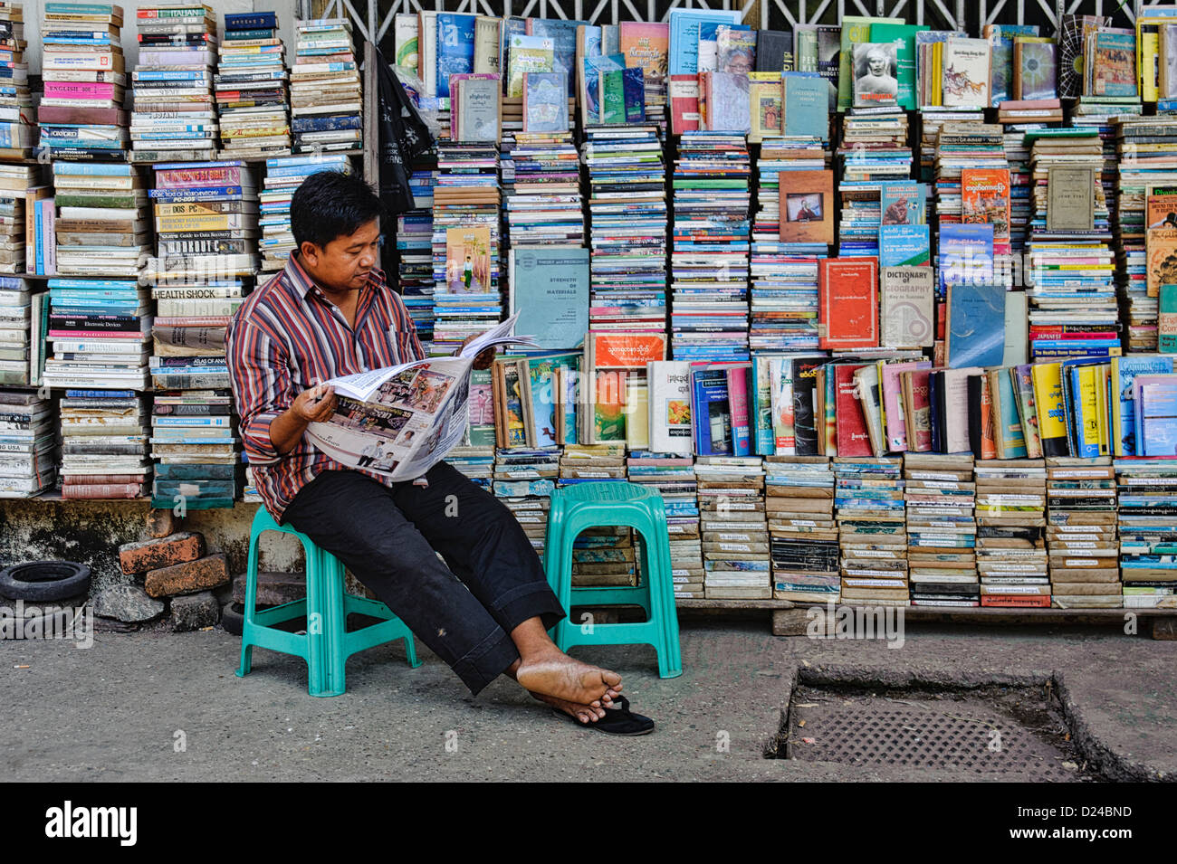 Books on sale on 'Book street' in Yangon, with vendor reading the ...