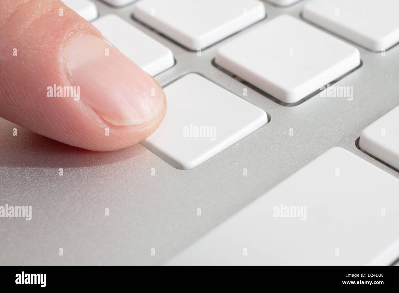 Finger is pressing key of a modern stylish aluminium white computer ...