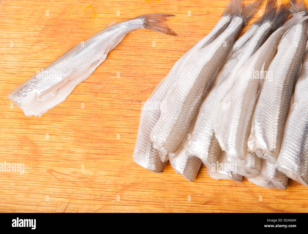 many uncooked trunk small fish on wood board Stock Photo - Alamy