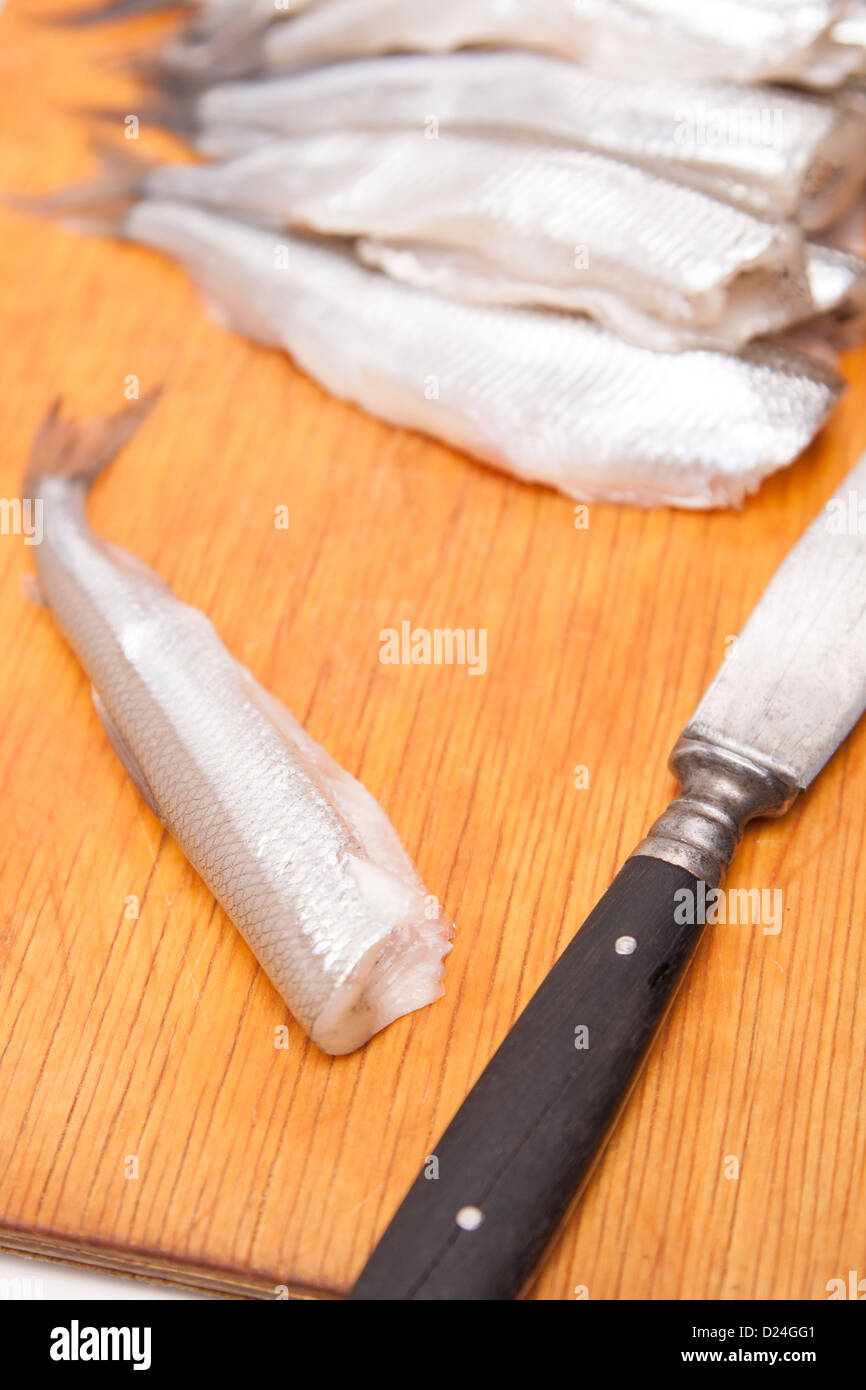 many uncooked trunk small fish on wood board Stock Photo - Alamy