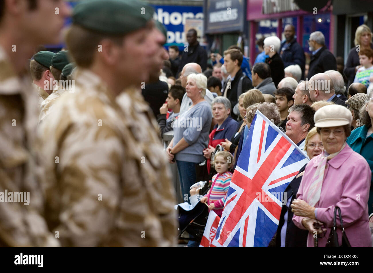 A crowd of people with a Union Jack at a welcome home parade for ...
