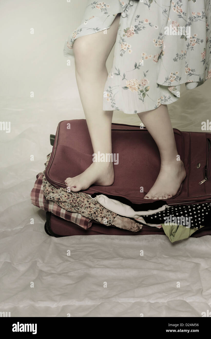 a woman tries to close a suitcase with her feet Stock Photo - Alamy