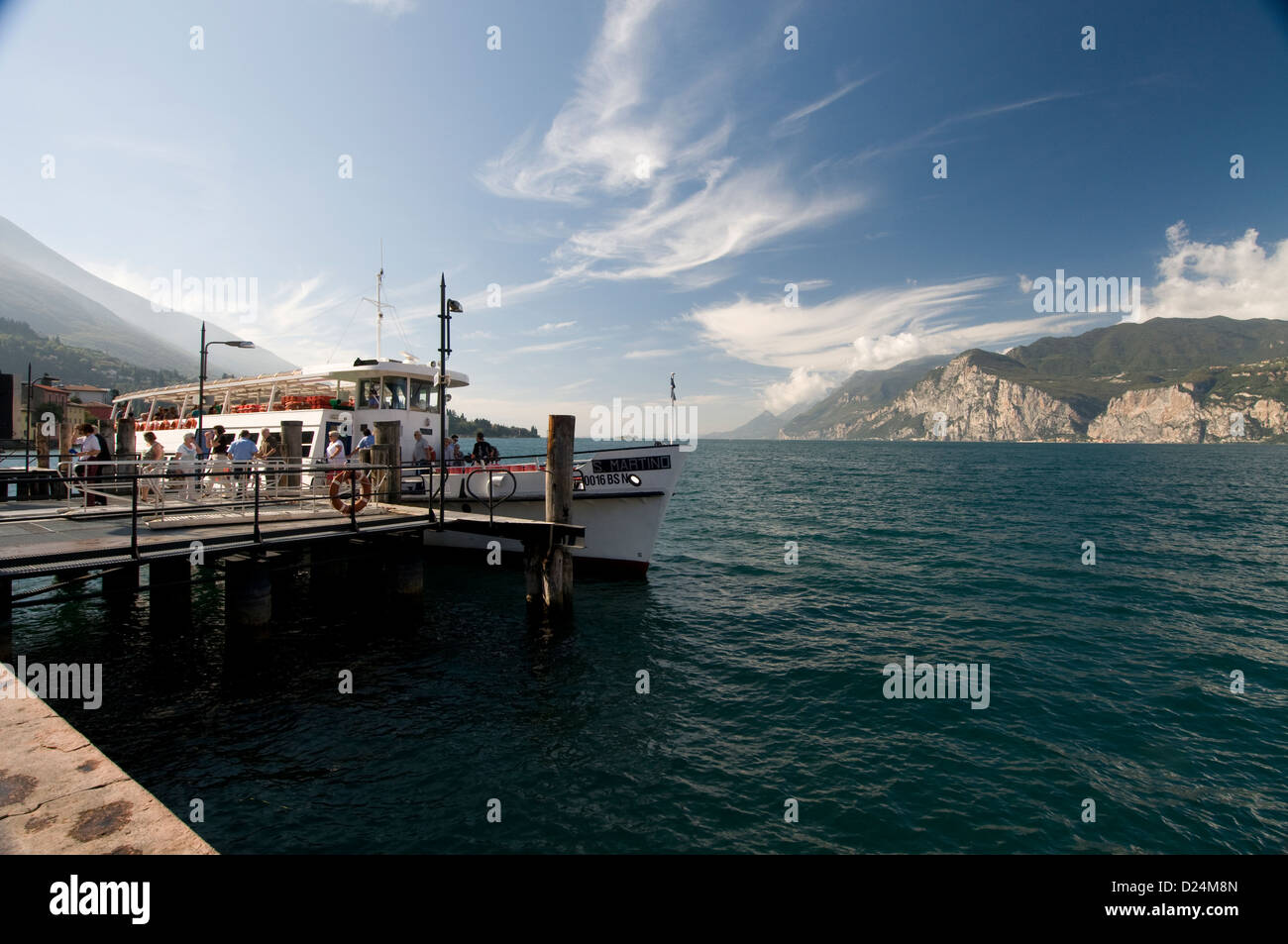 A Lake Garda passenger ferry moored beside a jetty at the medieval town ...