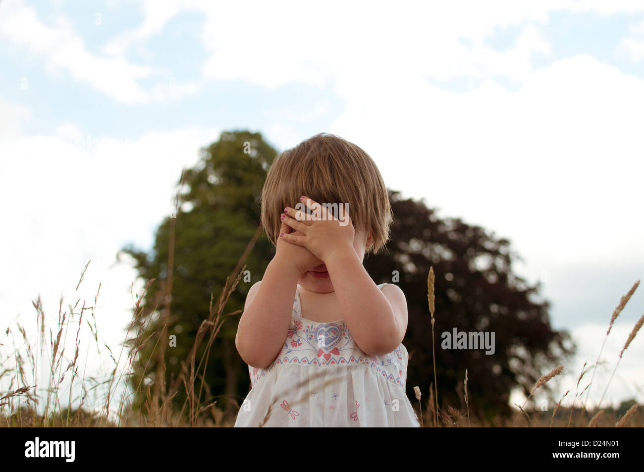 A little girl playing hide and seek outdoors Stock Photo - Alamy
