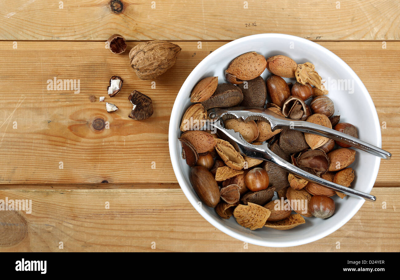 mixed nuts in a white bowl with a metal nut cracker, photographed on ...