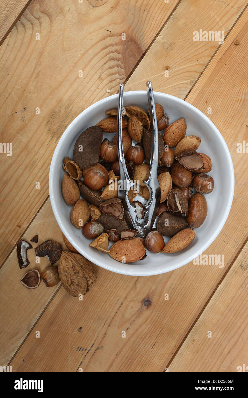 mixed nuts in a white bowl with a metal nut cracker, photographed on ...
