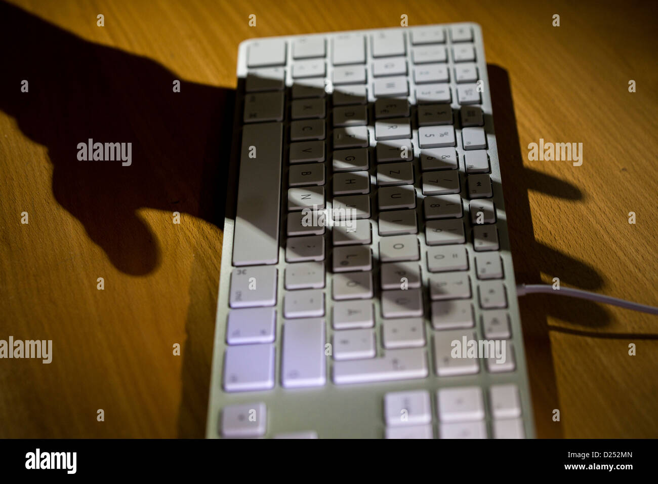 Shadow of a hand over a computer keyboard Stock Photo - Alamy