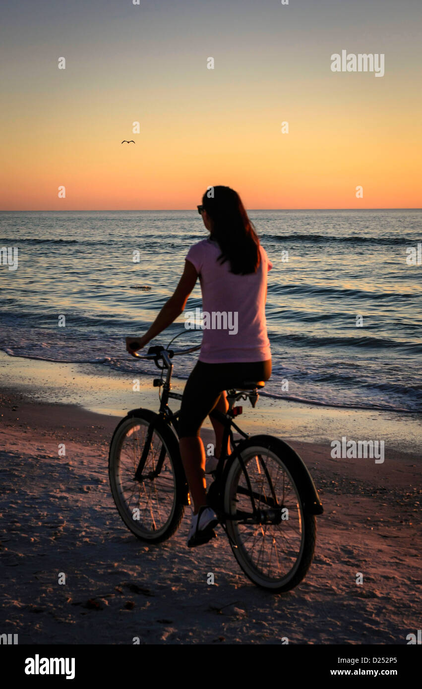 Young woman rides her bicycle along the Siesta Key beach in Florida at ...