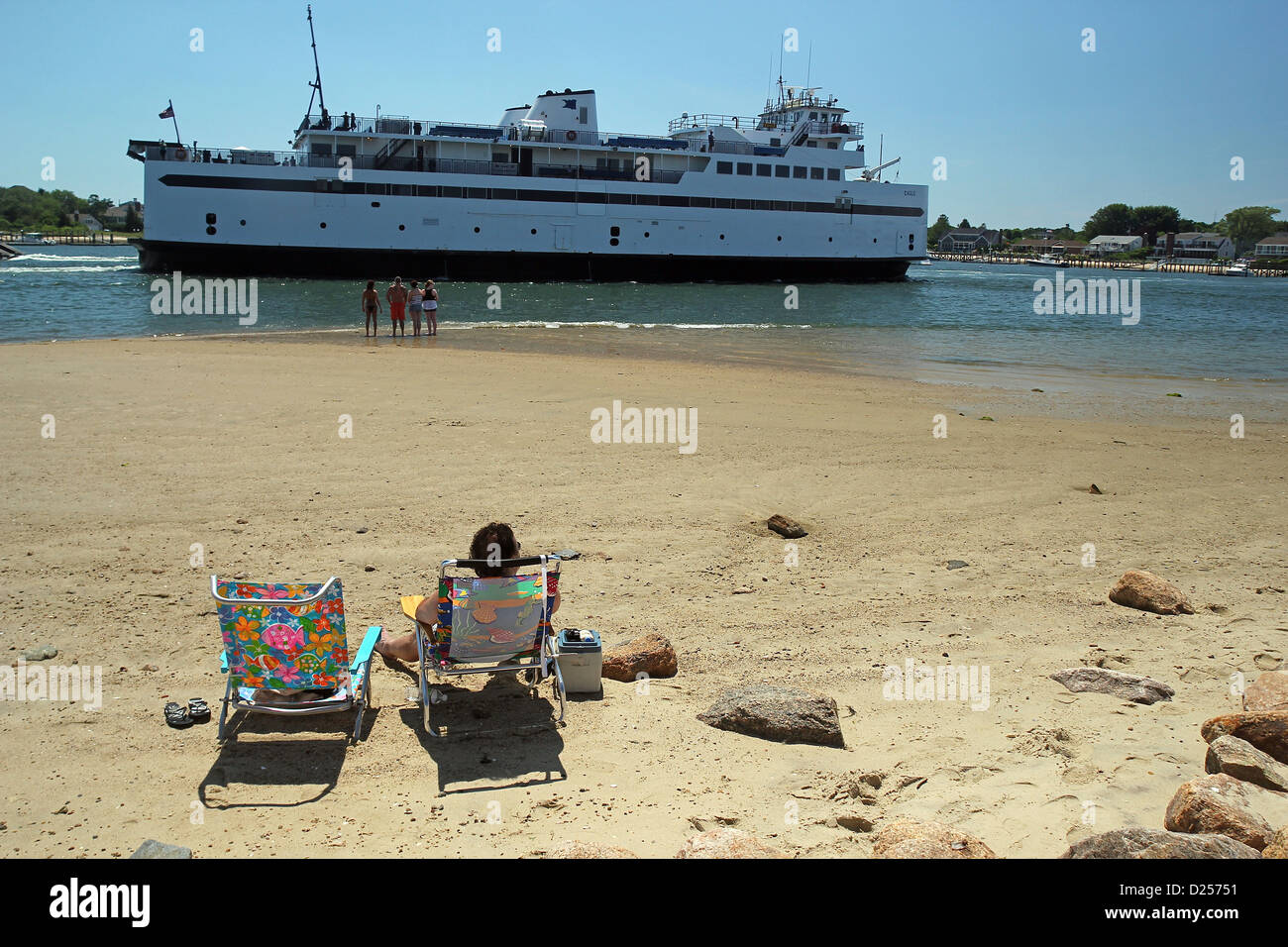 People watch as a ferry passes near the shore at Bayview Beach, Cape ...