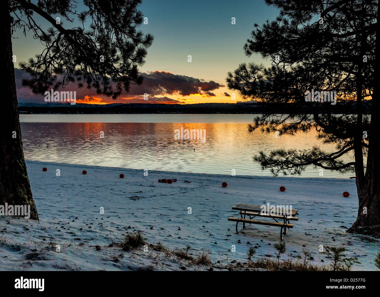 Sunset reflection on a lake with pine trees and picnic table Stock ...