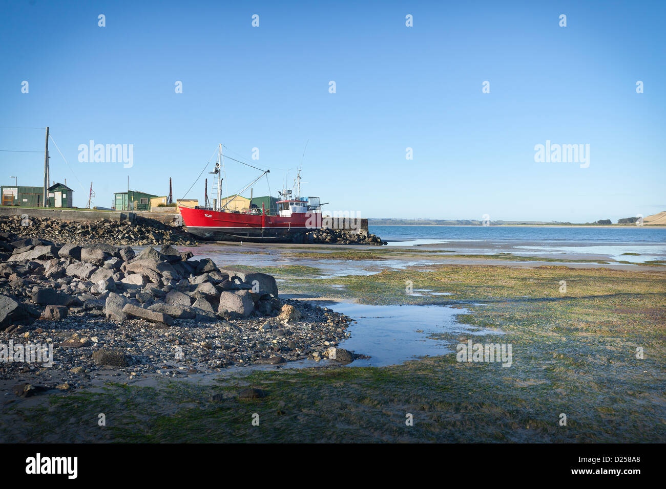 Seascape looking over pier at low tide with fishing boat on rocks Stock ...