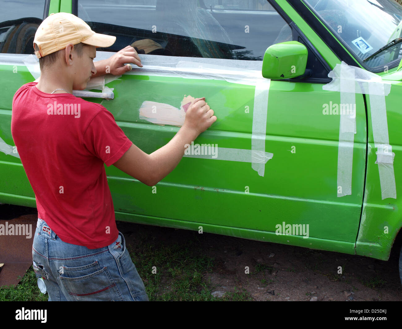 Young boy repair green color car body sanding putty Stock Photo - Alamy