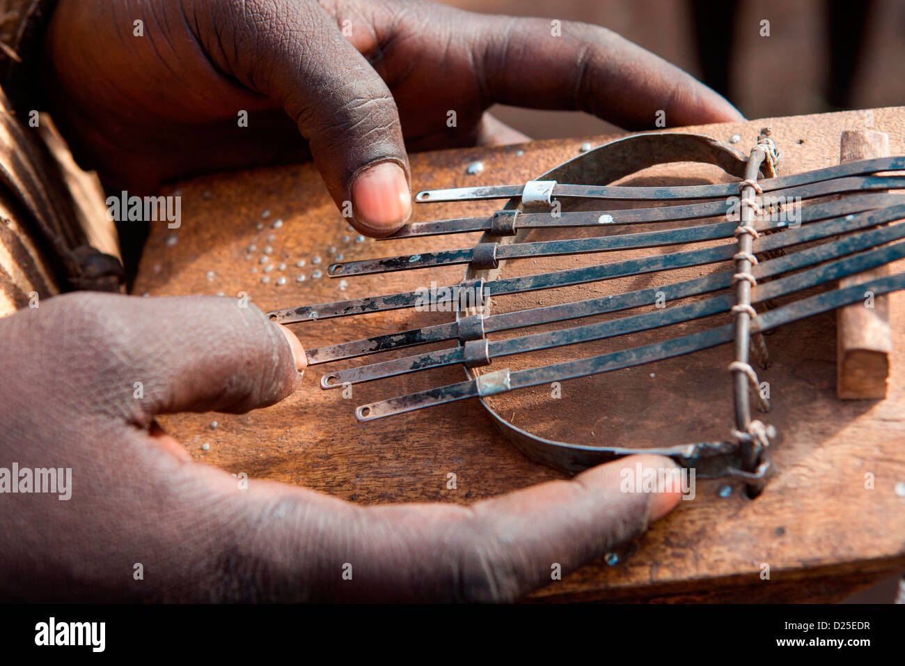 Detail of a Mursi tribeswoman playing a handmade musical instrument in ...