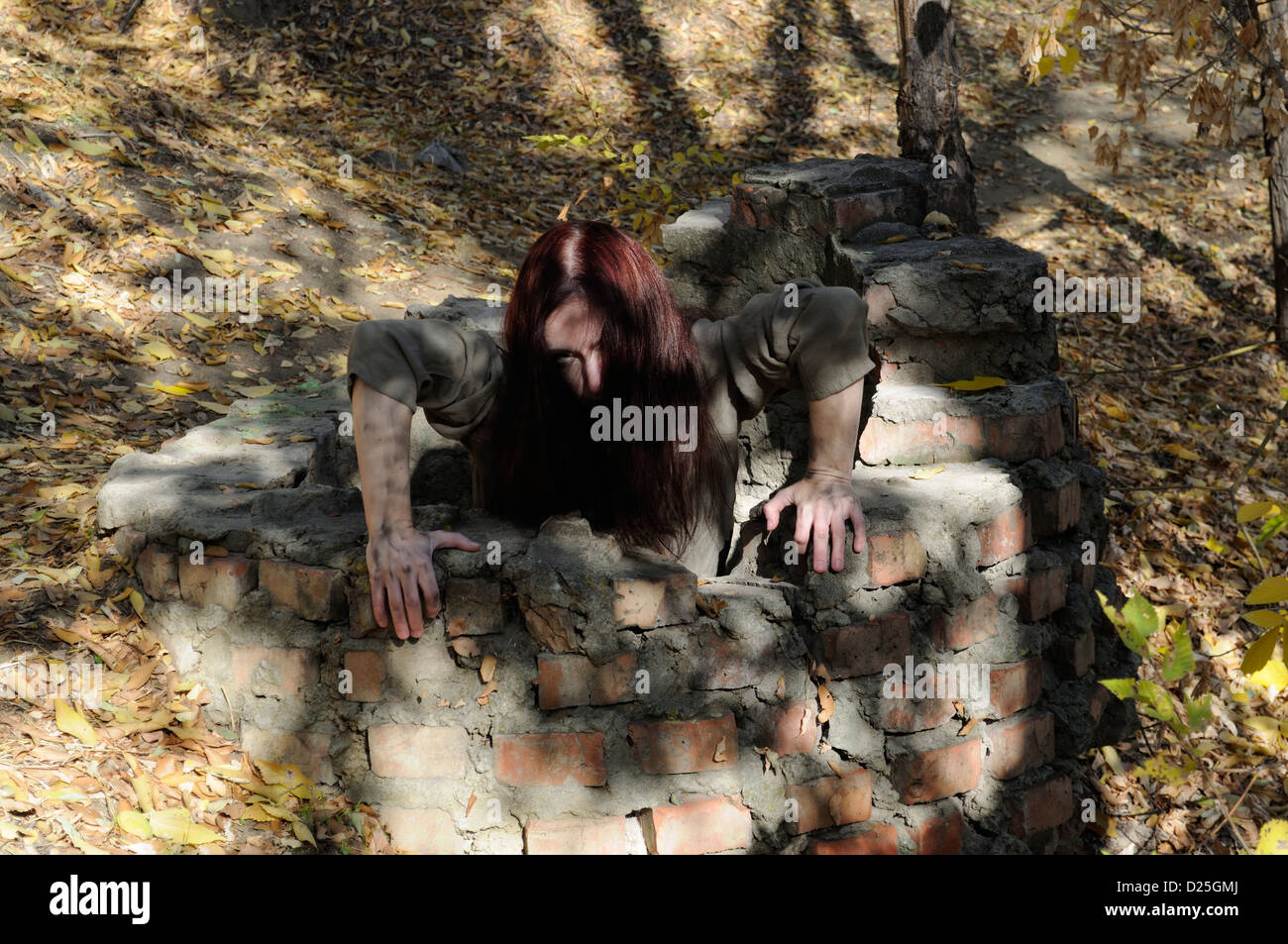 Horror woman in an old brick well, crawling out Stock Photo - Alamy