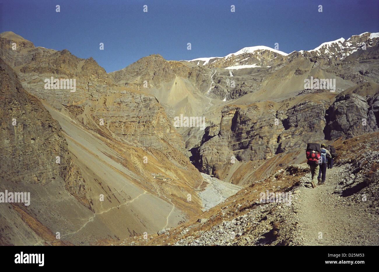 Trekkers on high track on east of Jharsang Khola with huts of Thorong ...