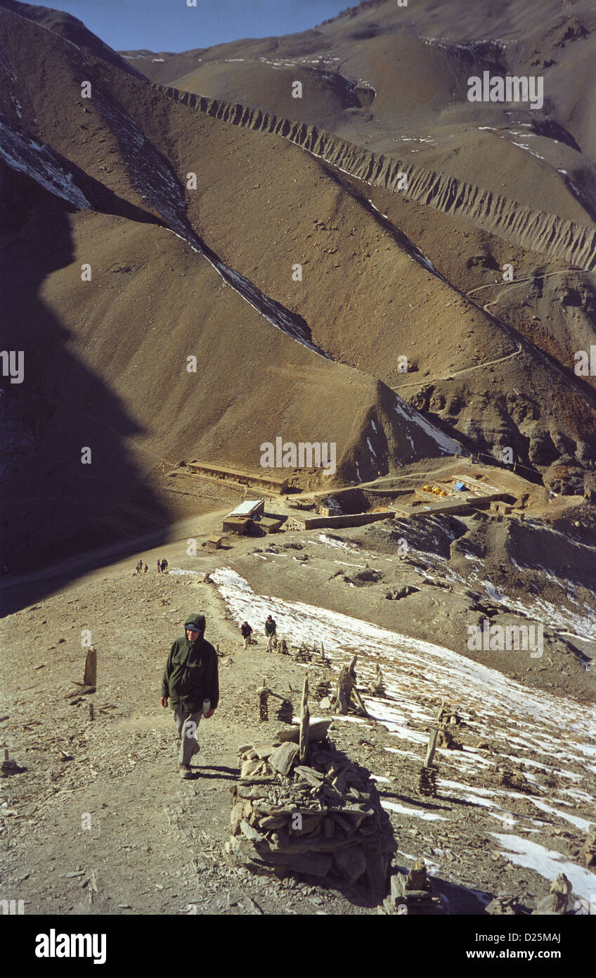 Trekkers climbing path to rocky peak above Thorong Phedi high camp east ...
