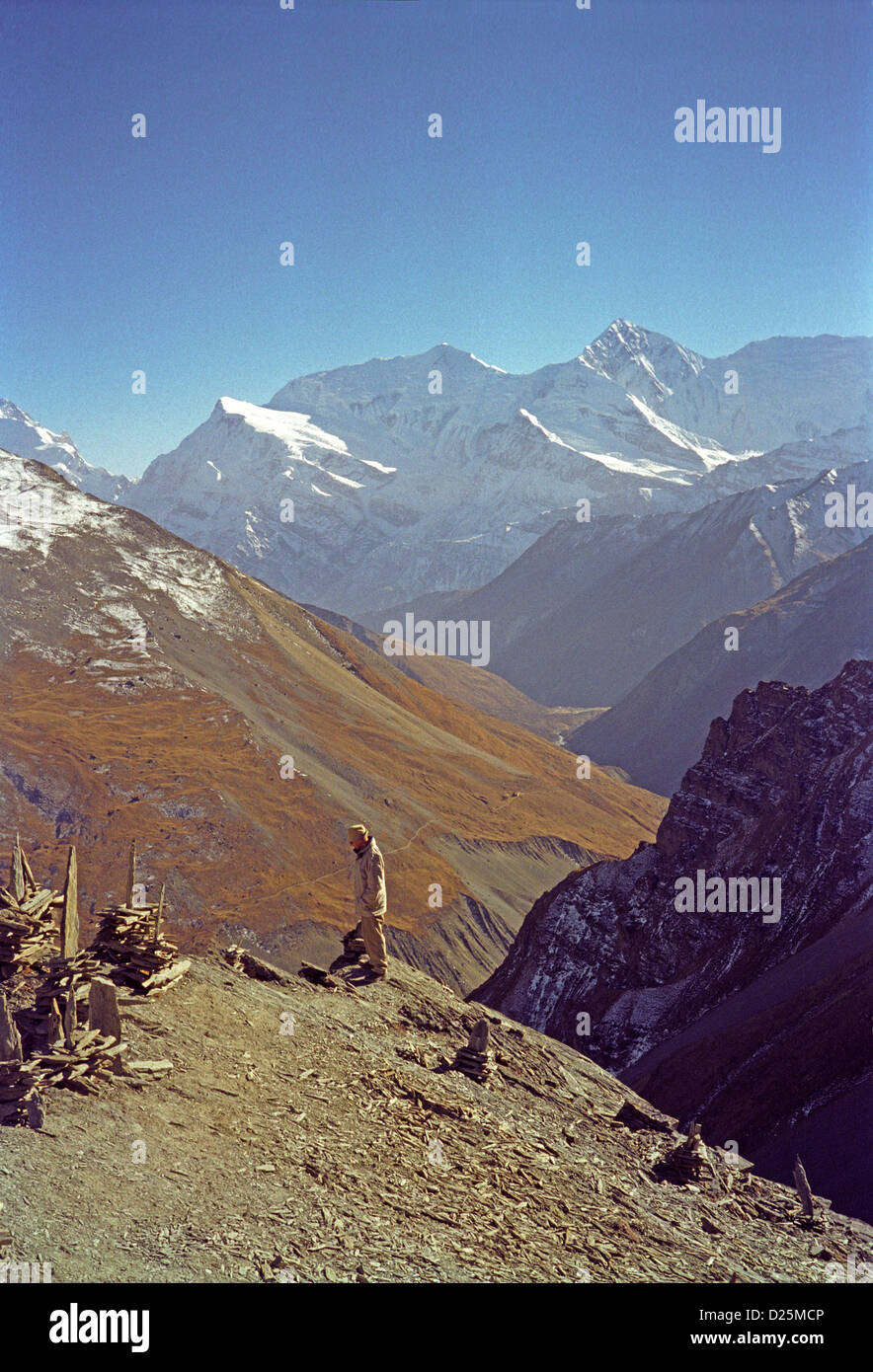 Lone trekker looks down Jharsang Khola valley from rock peak above ...