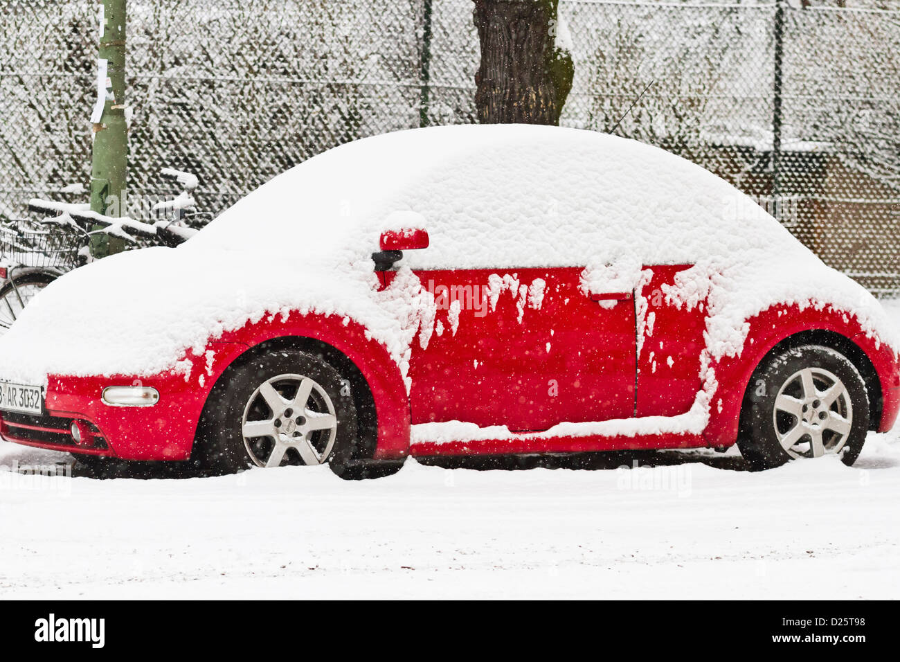 A red Volkswagen Beetle covered in snow during winter in Berlin ...