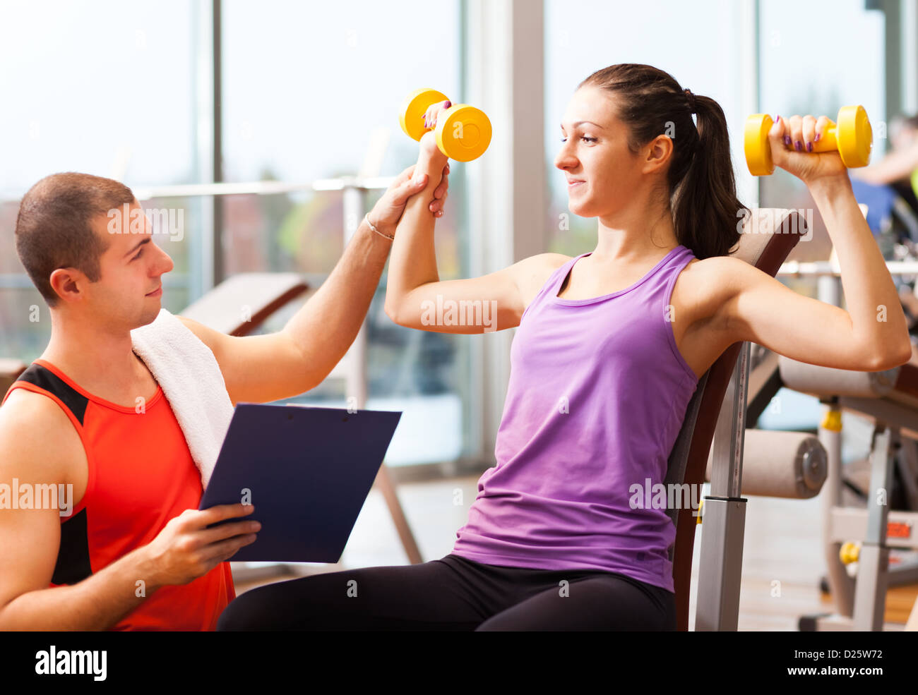 Personal trainer showing an exercise to a woman Stock Photo - Alamy