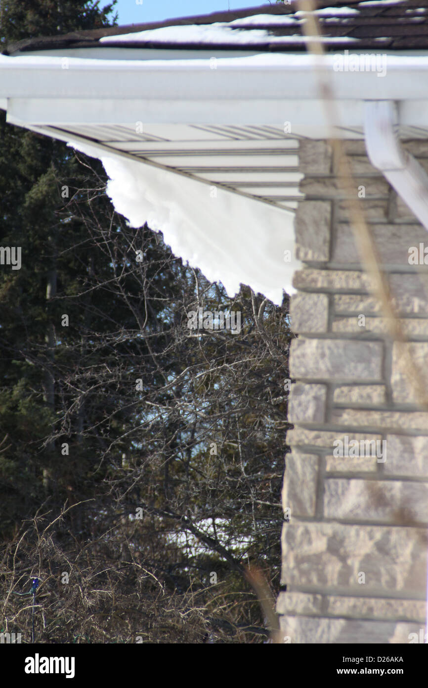 Snow and icicles hanging from the eaves of a house Stock Photo - Alamy