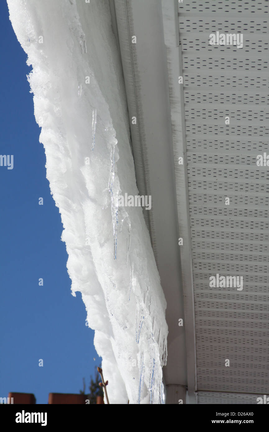 Snow and icicles hanging from the eaves of a house Stock Photo - Alamy