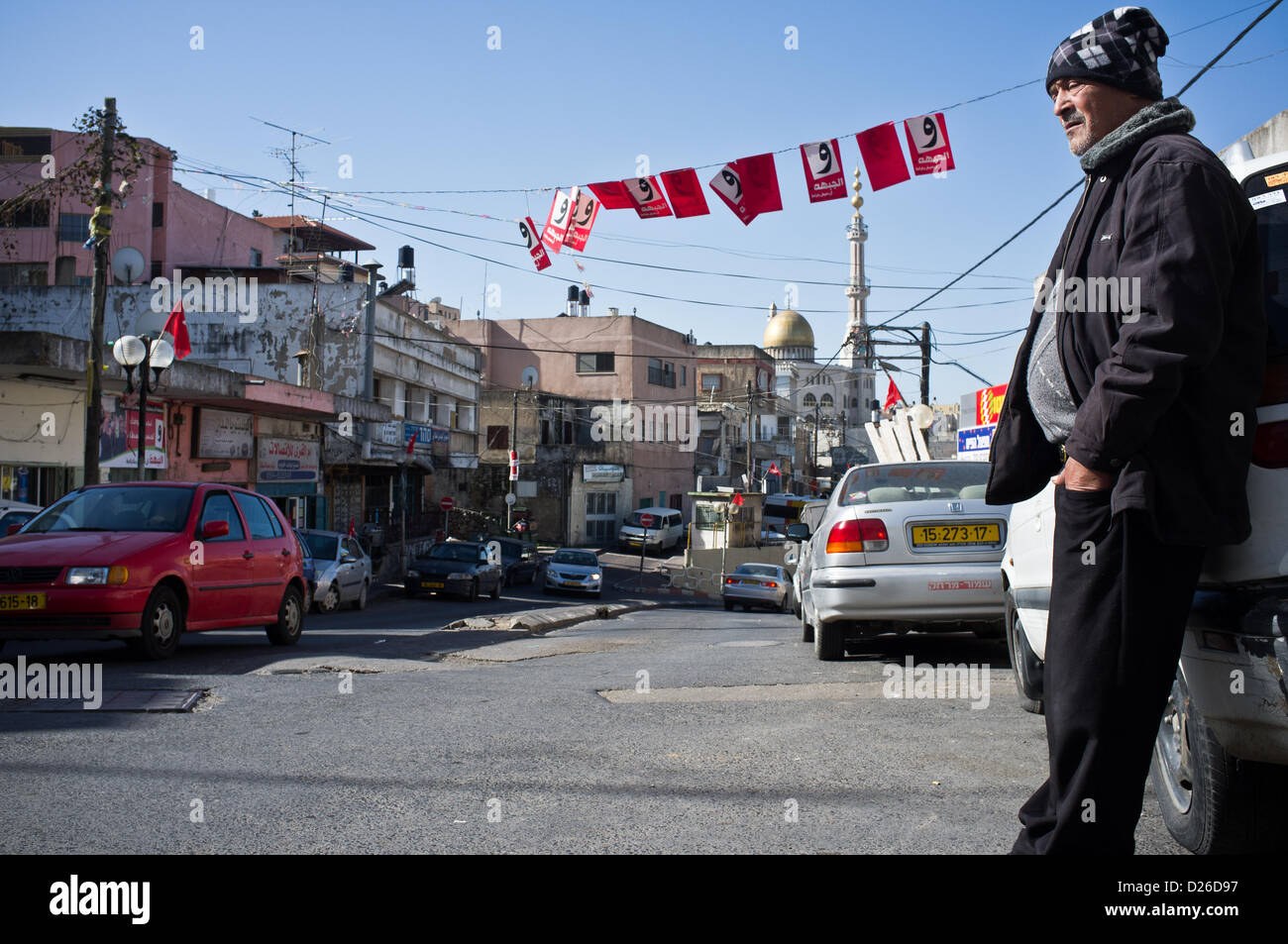 A man stands in an Um El-Fahm street as a Hadash Party banner, the ...