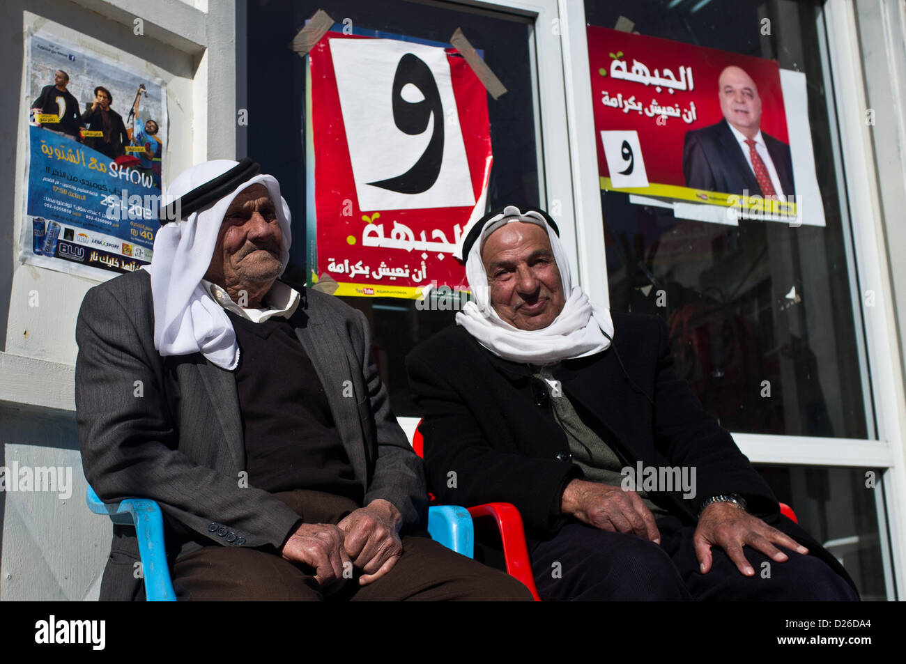 Two men wearing traditional Arab kaffiyahs on their heads sit outside ...