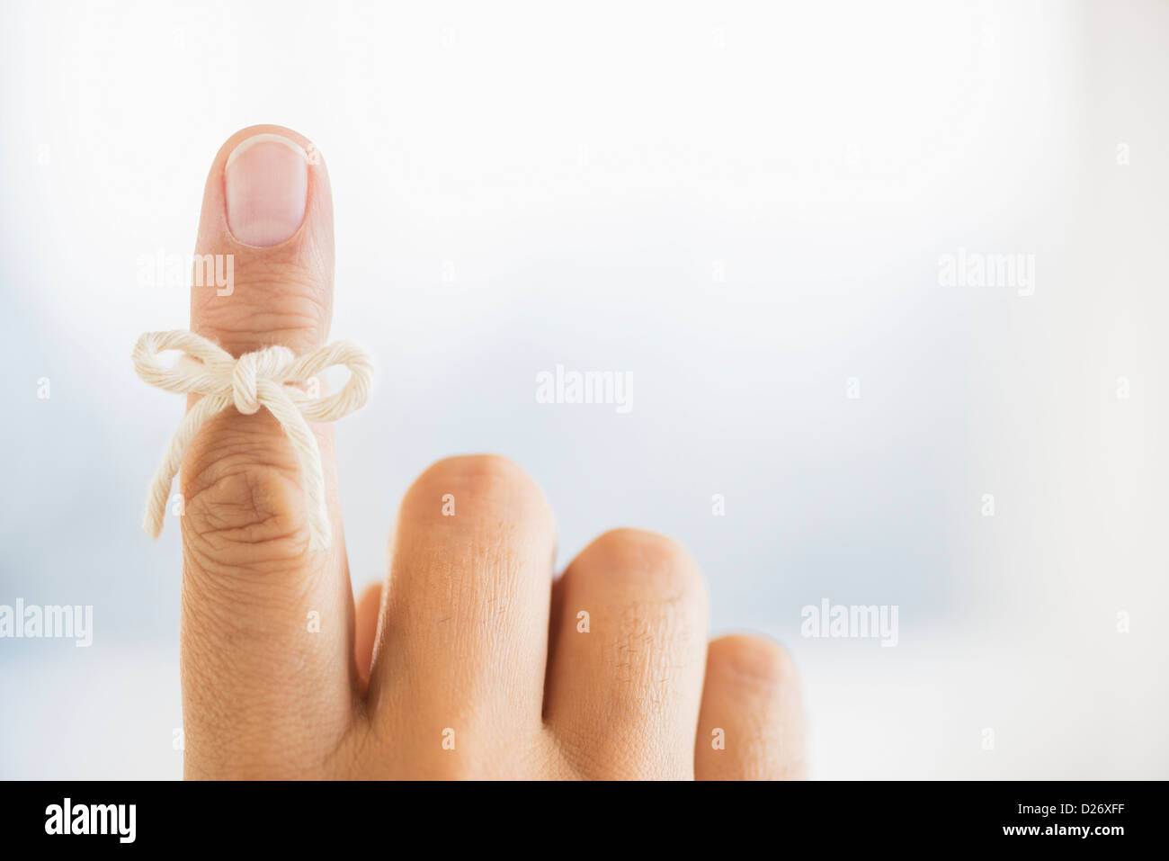 Hand with reminder bow on finger Stock Photo - Alamy