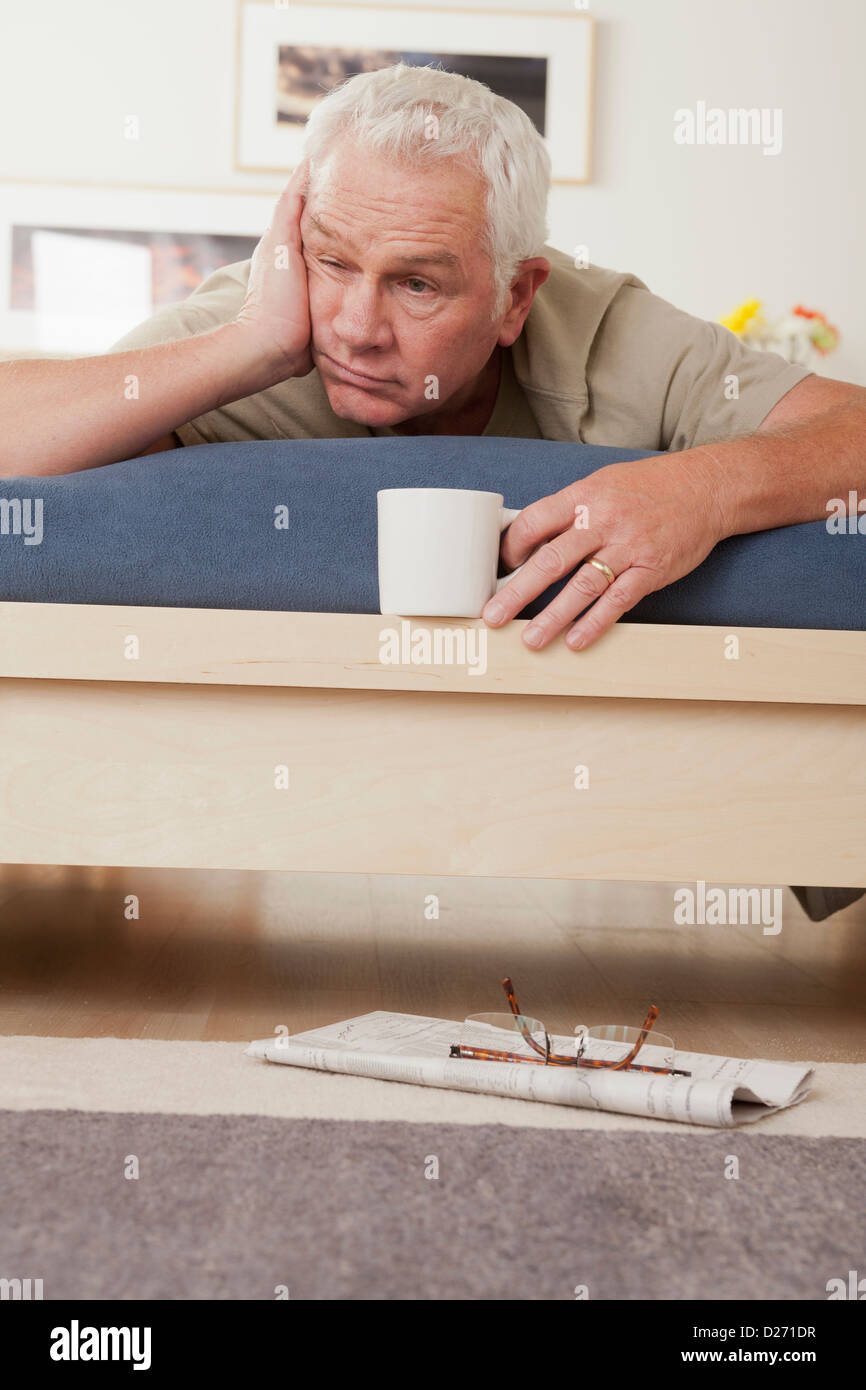 Tired senior man holding coffee cup lying on bed Stock Photo - Alamy