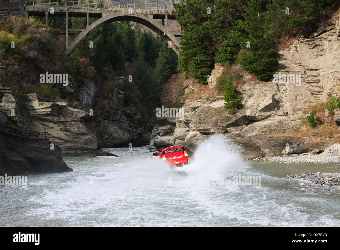Jet boat speeding into the Shotover River canyon under the Edith Cavell ...