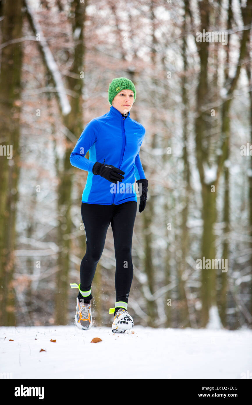 Young woman jogging in winter, through a snowy landscape Stock Photo ...