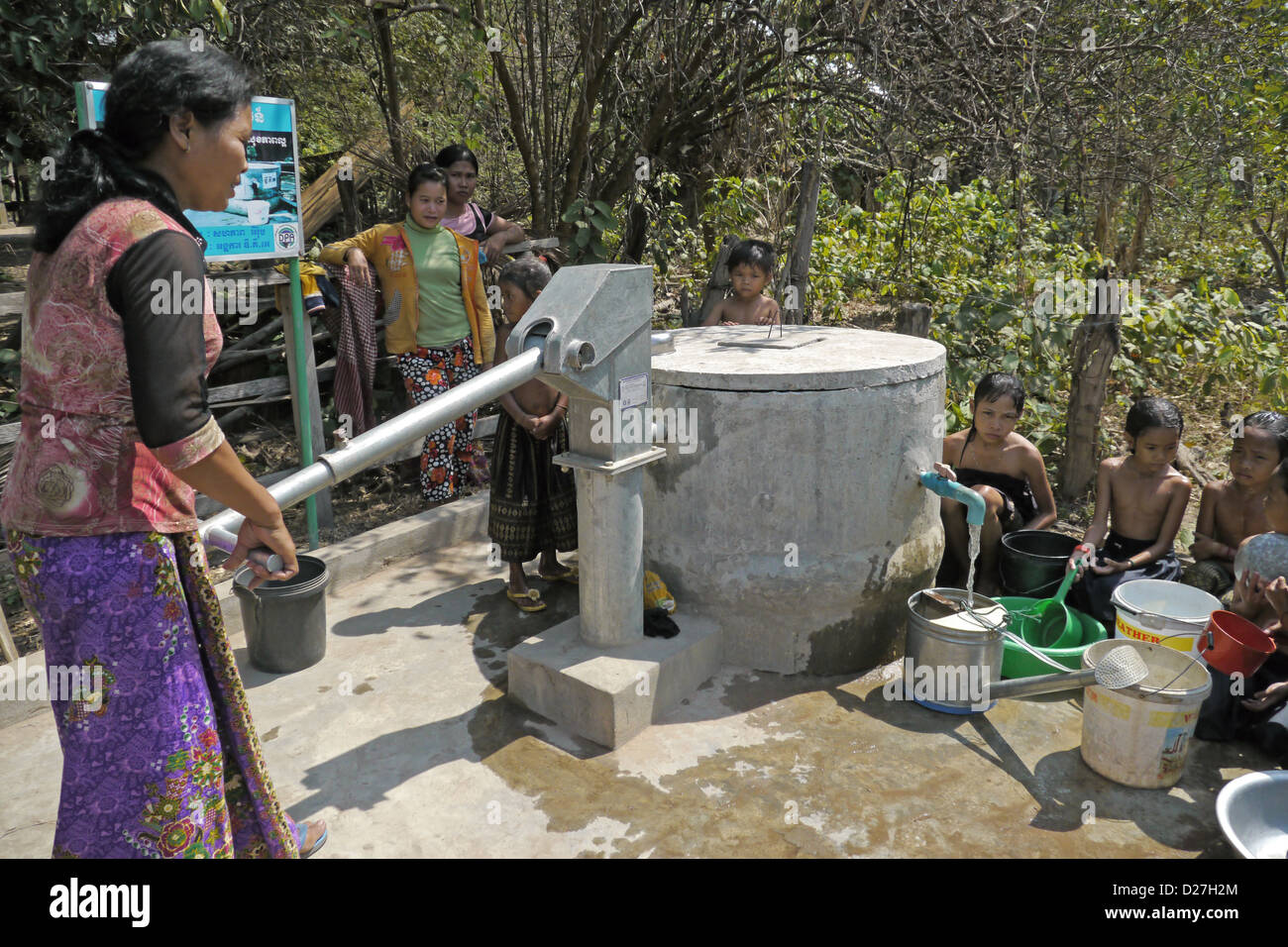 Cambodia Woman pumping water at well while children wash Stock Photo ...