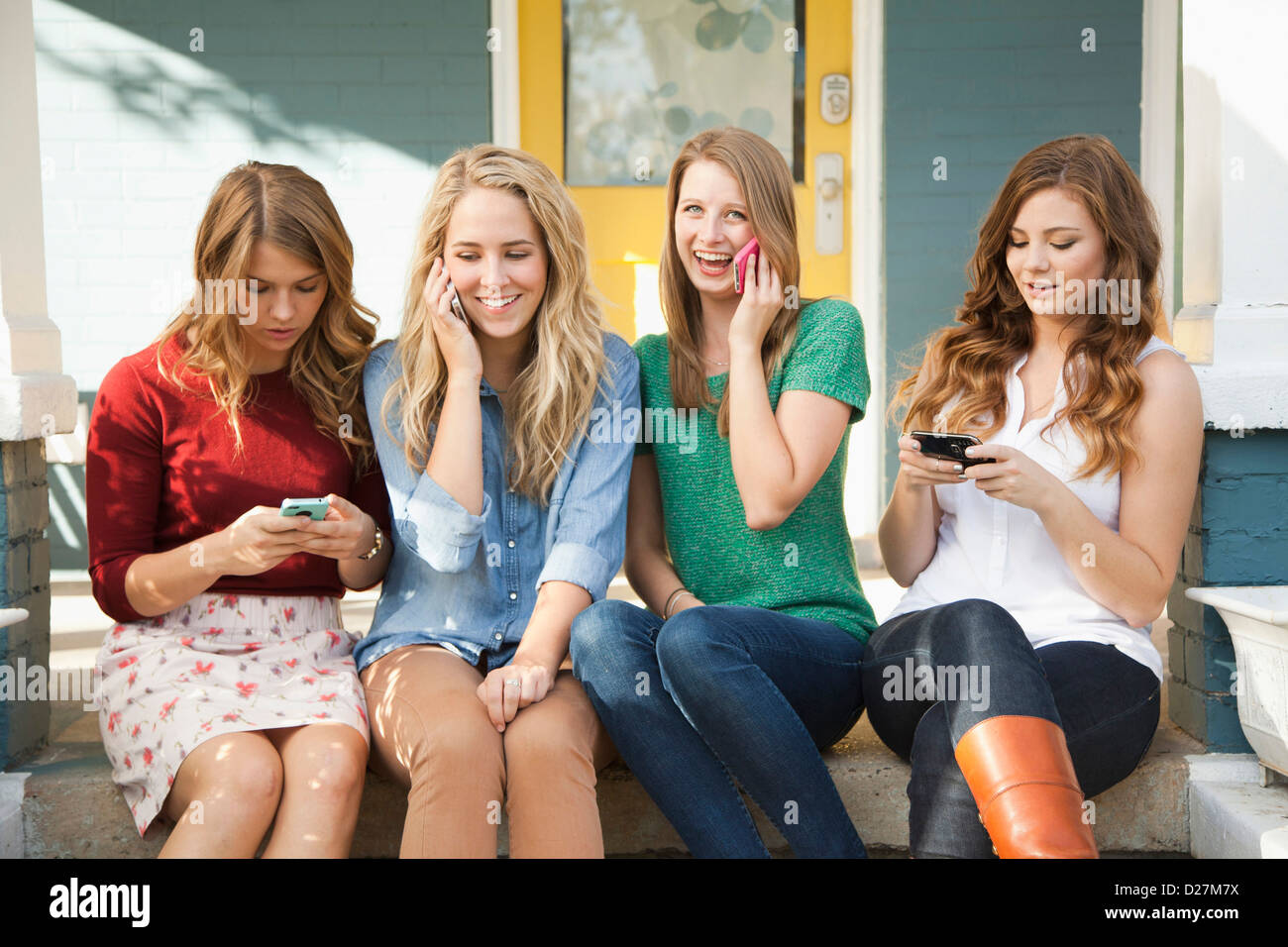 USA, Utah, Provo, Four friends sitting on porch with their mobile ...