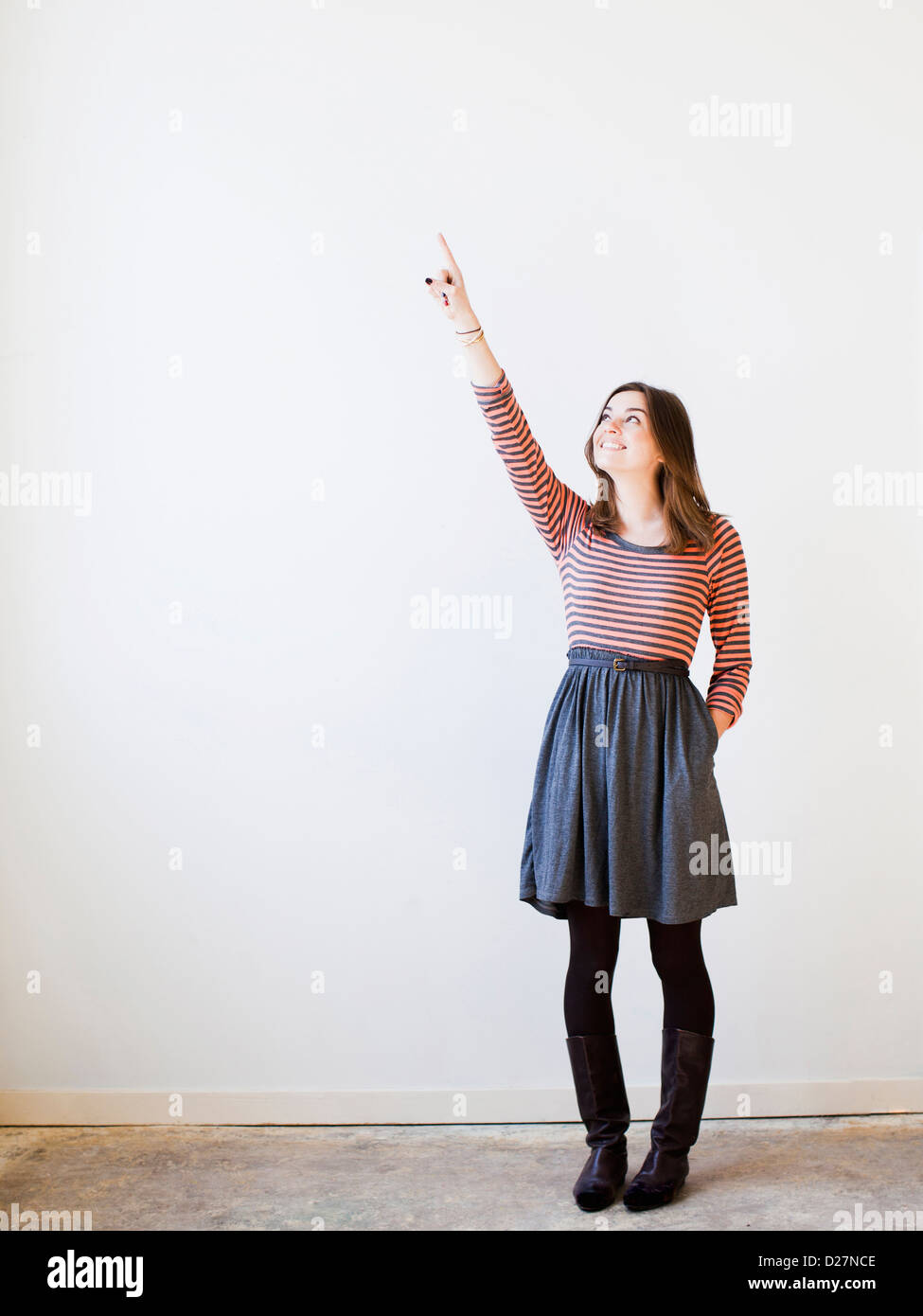 Studio shot young woman looking up and pointing Stock Photo - Alamy