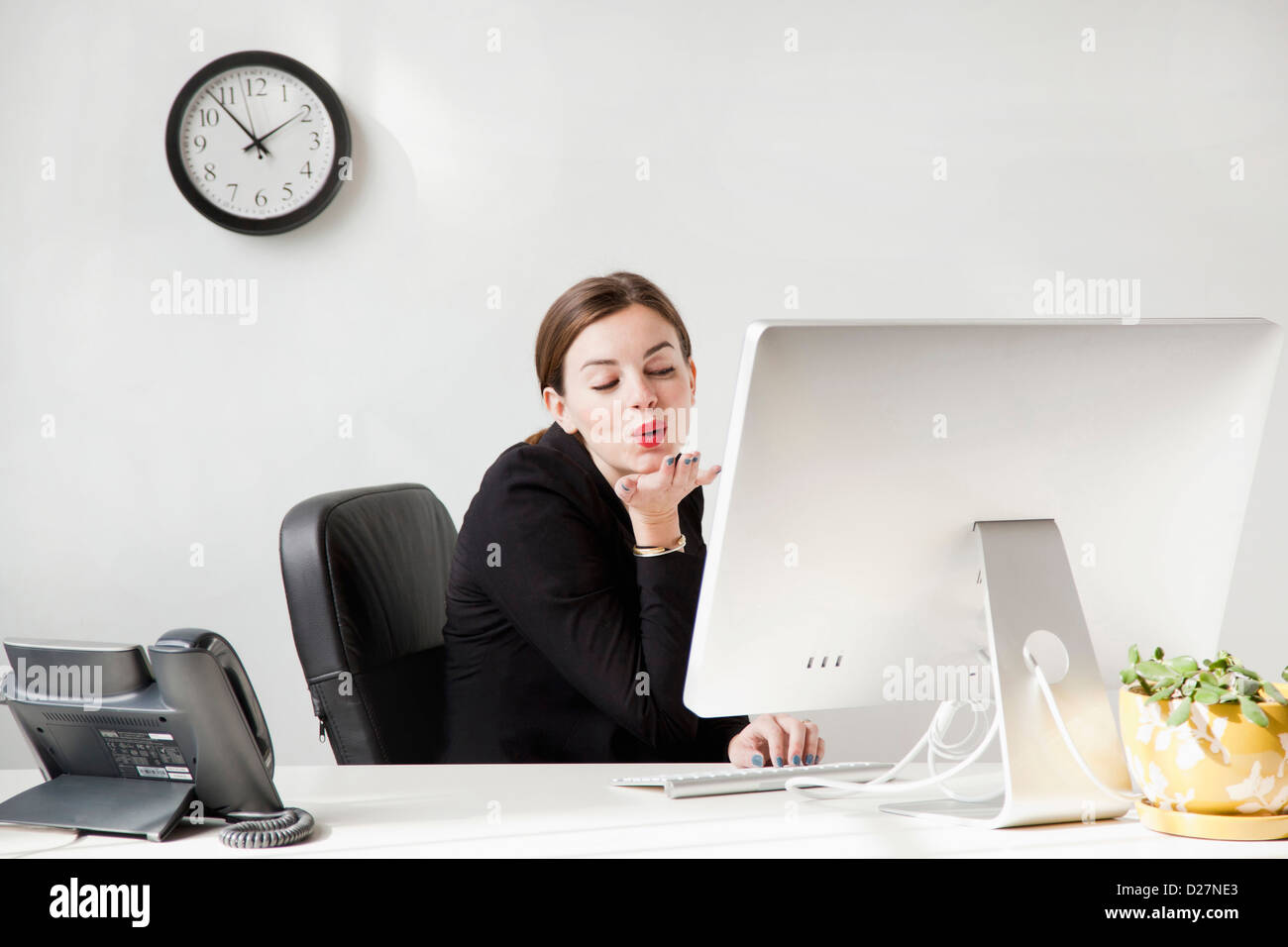 Studio shot of young woman blowing a kiss to computer monitor Stock ...