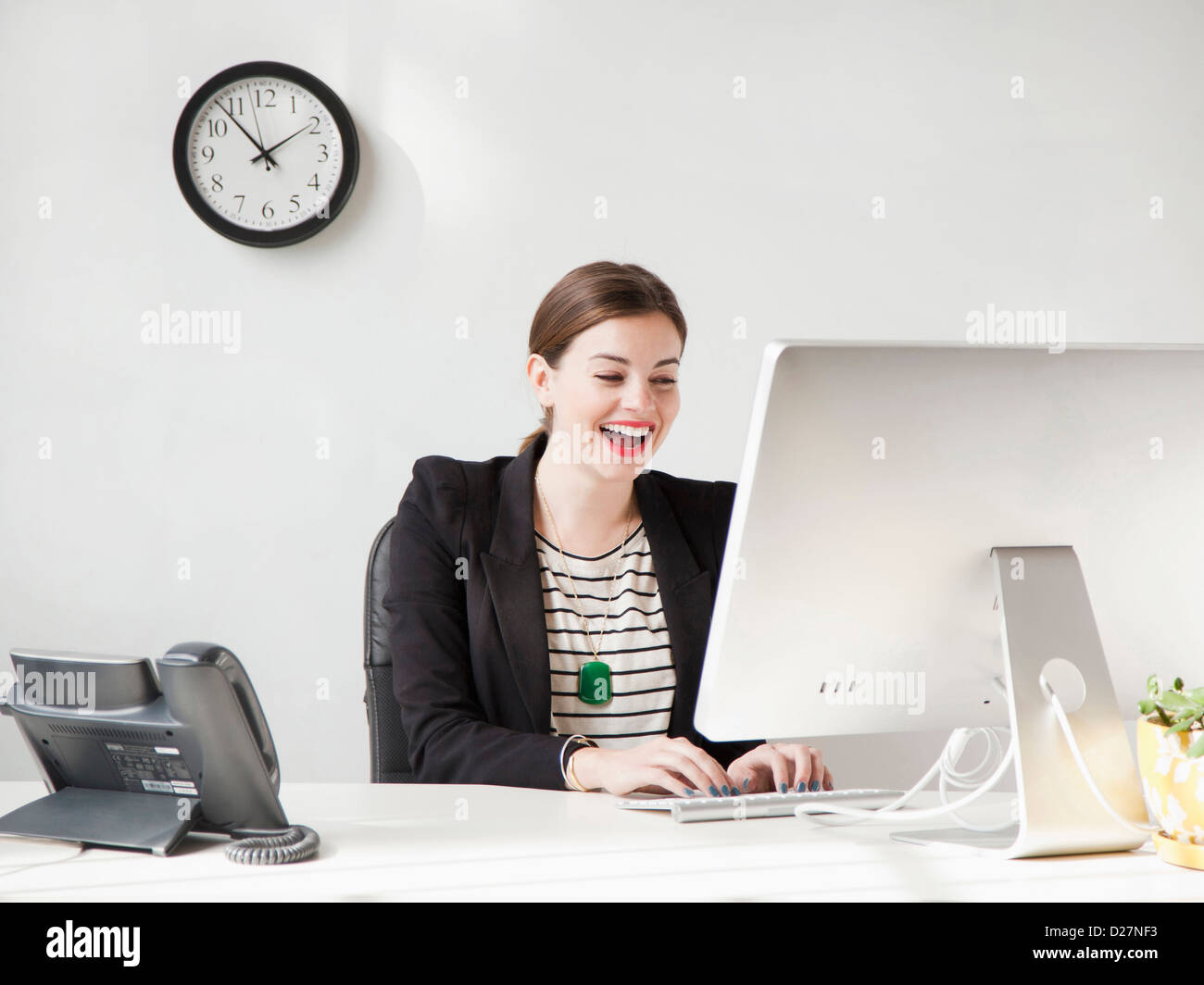 Studio shot of young woman working on computer and laughing Stock Photo ...