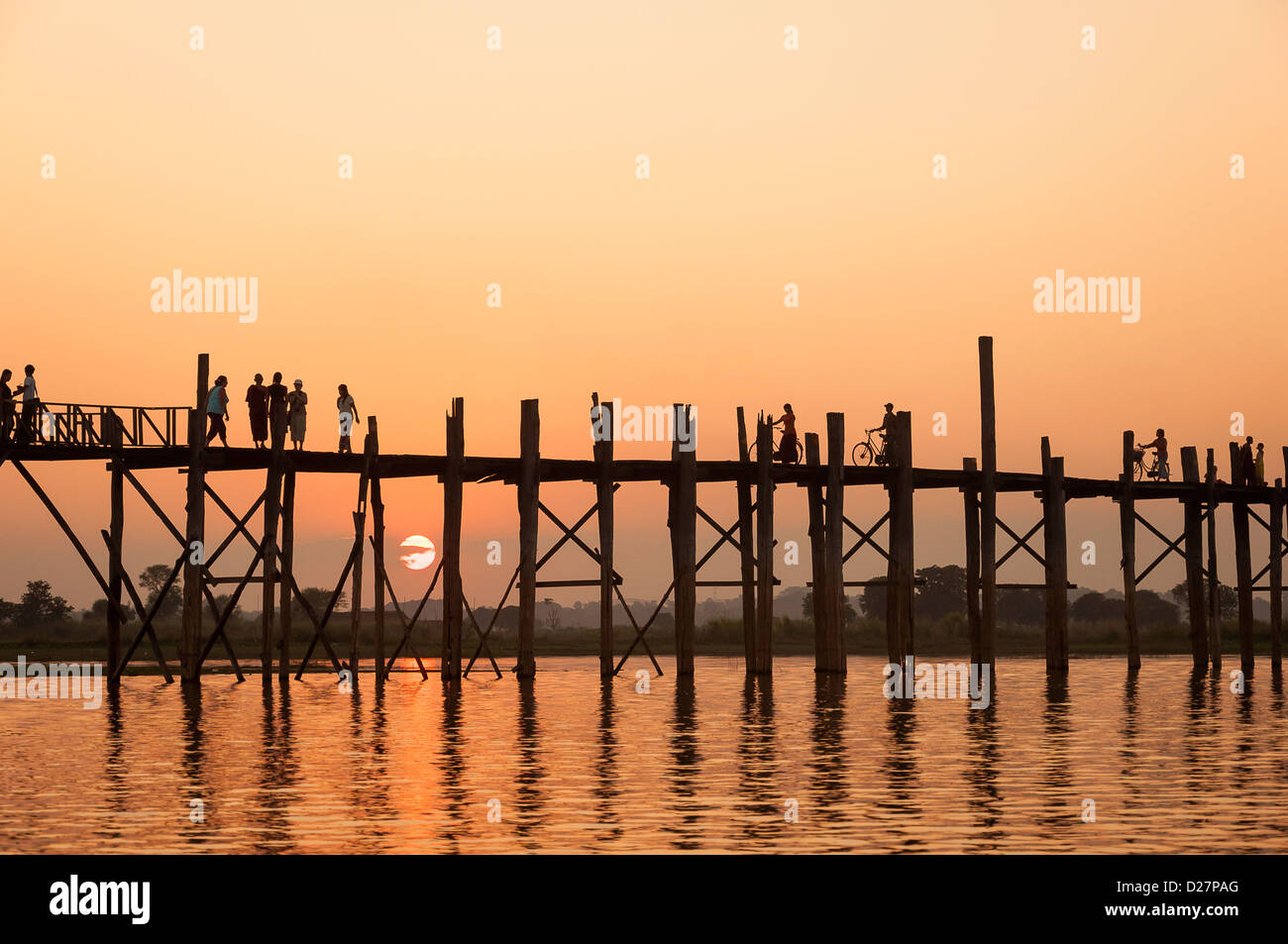 People walking over the world's longest teak bridge at sunset, Burma ...