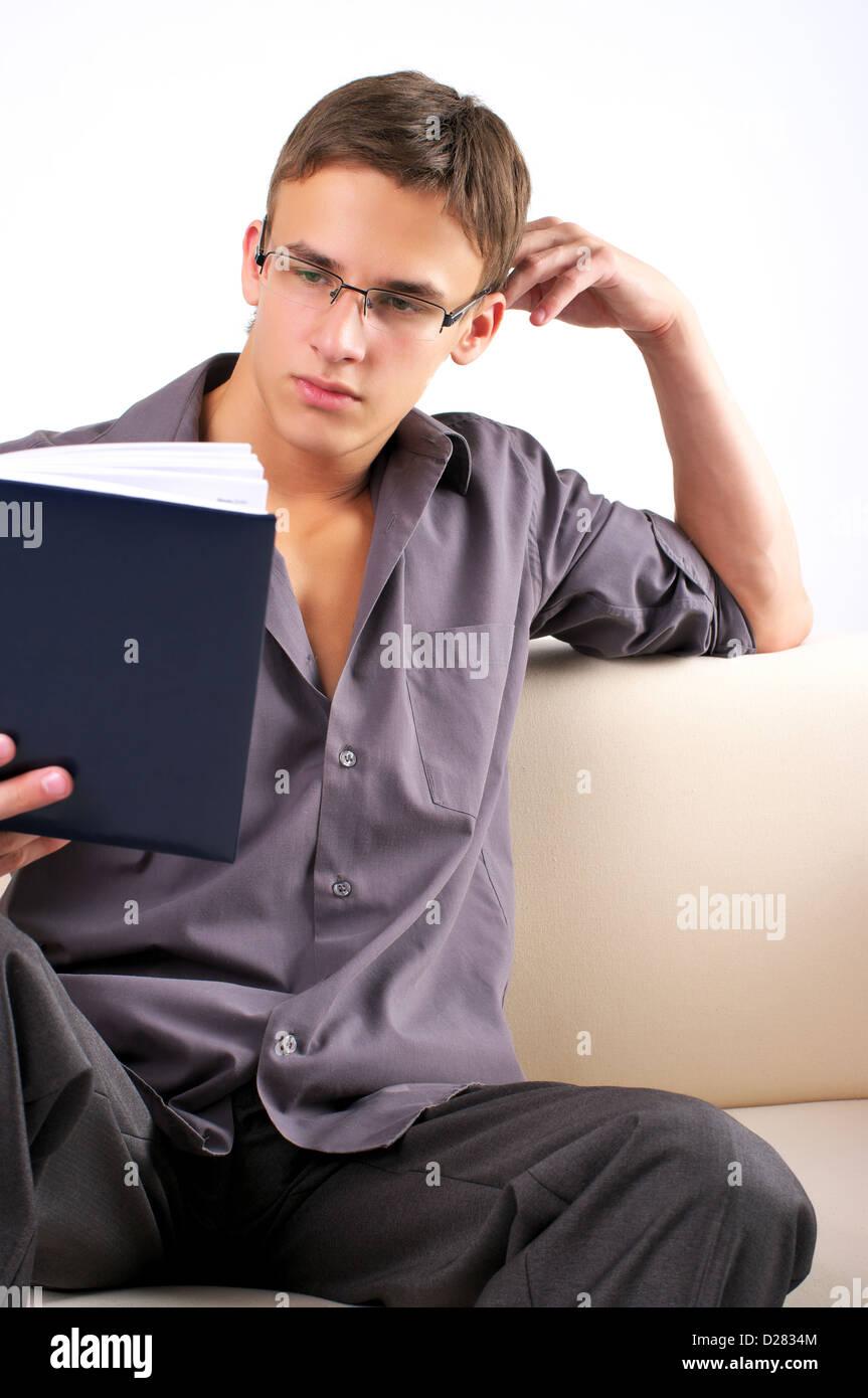 Young man reading book on the sofa at home Stock Photo - Alamy