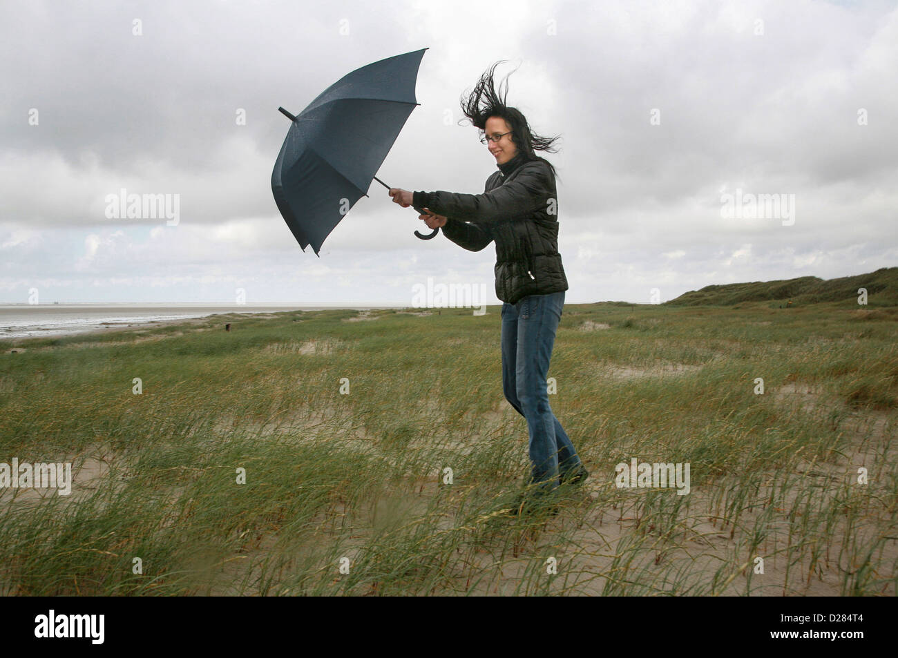 Sankt Peter-Ording, Germany, a woman is walking in wind and rain on the ...