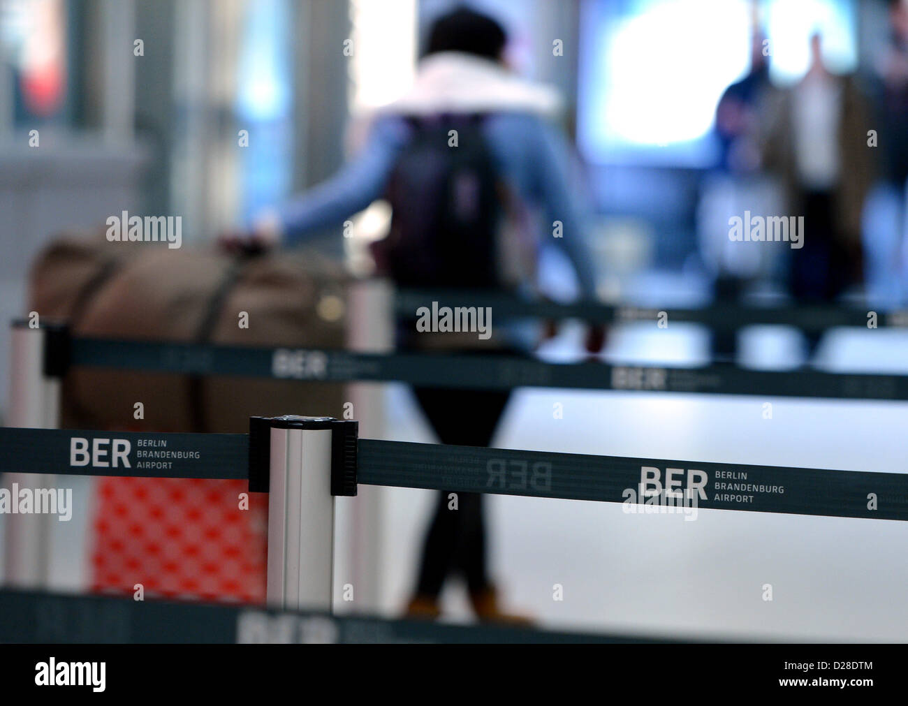 A passenger walks with her luggage behind barrier ropes in the busy ...