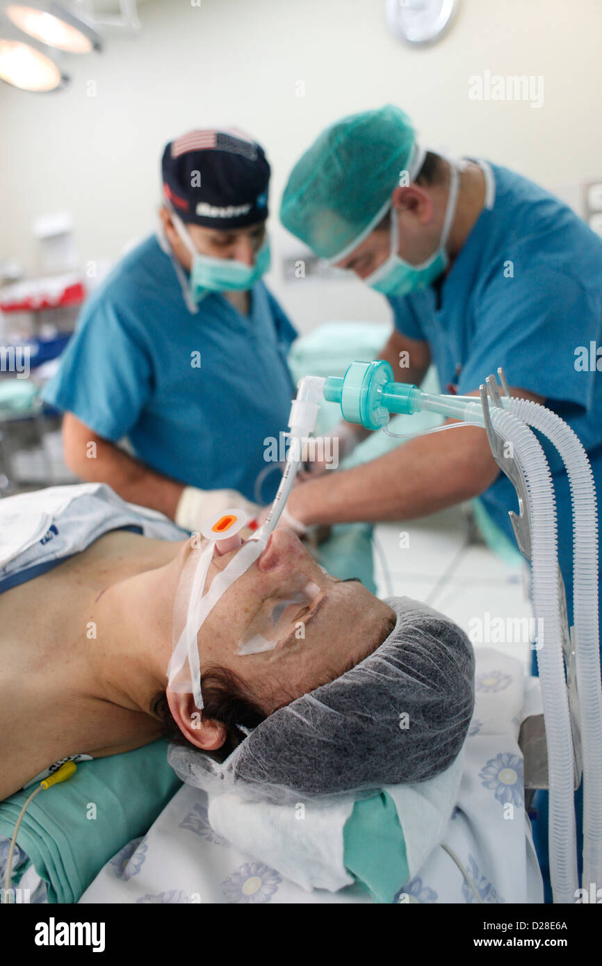 Surgeons wearing face mask performing operation in operating room in ...