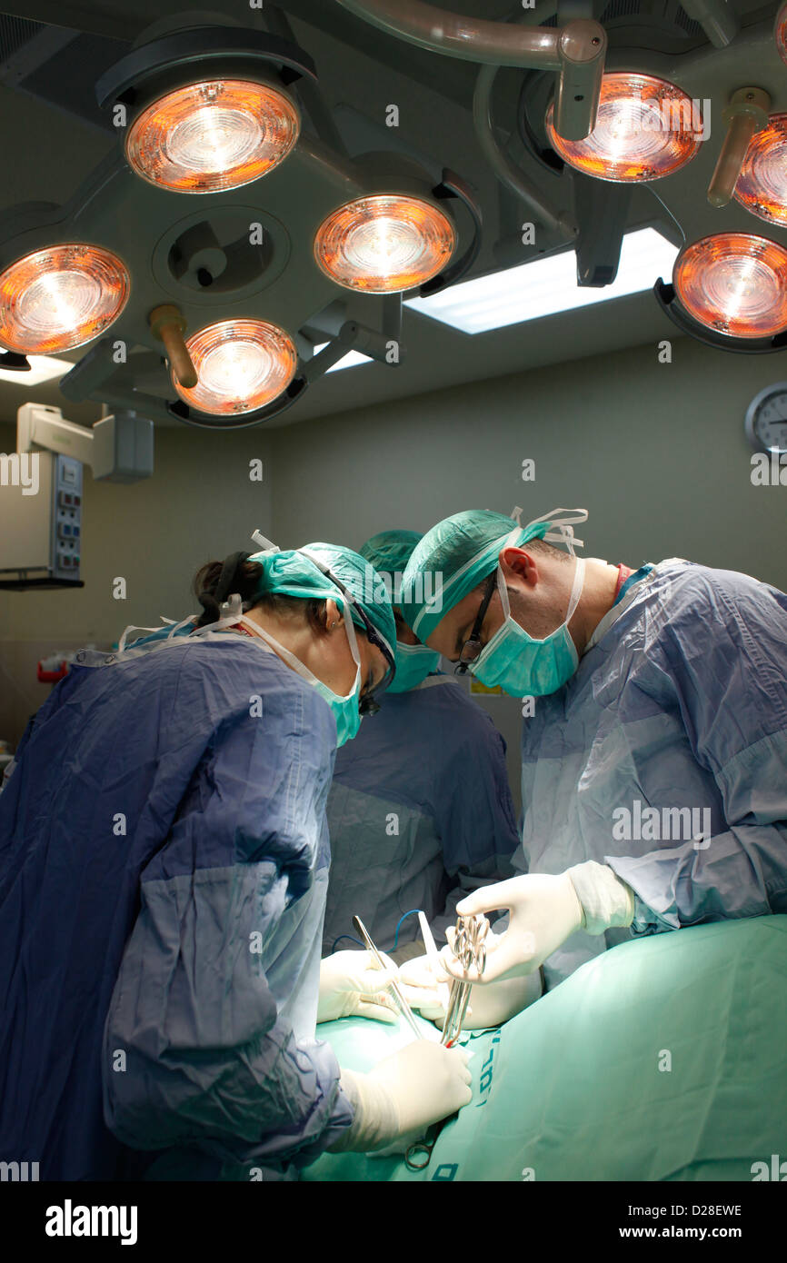 Surgeons wearing surgical mask performing operation in operating room ...