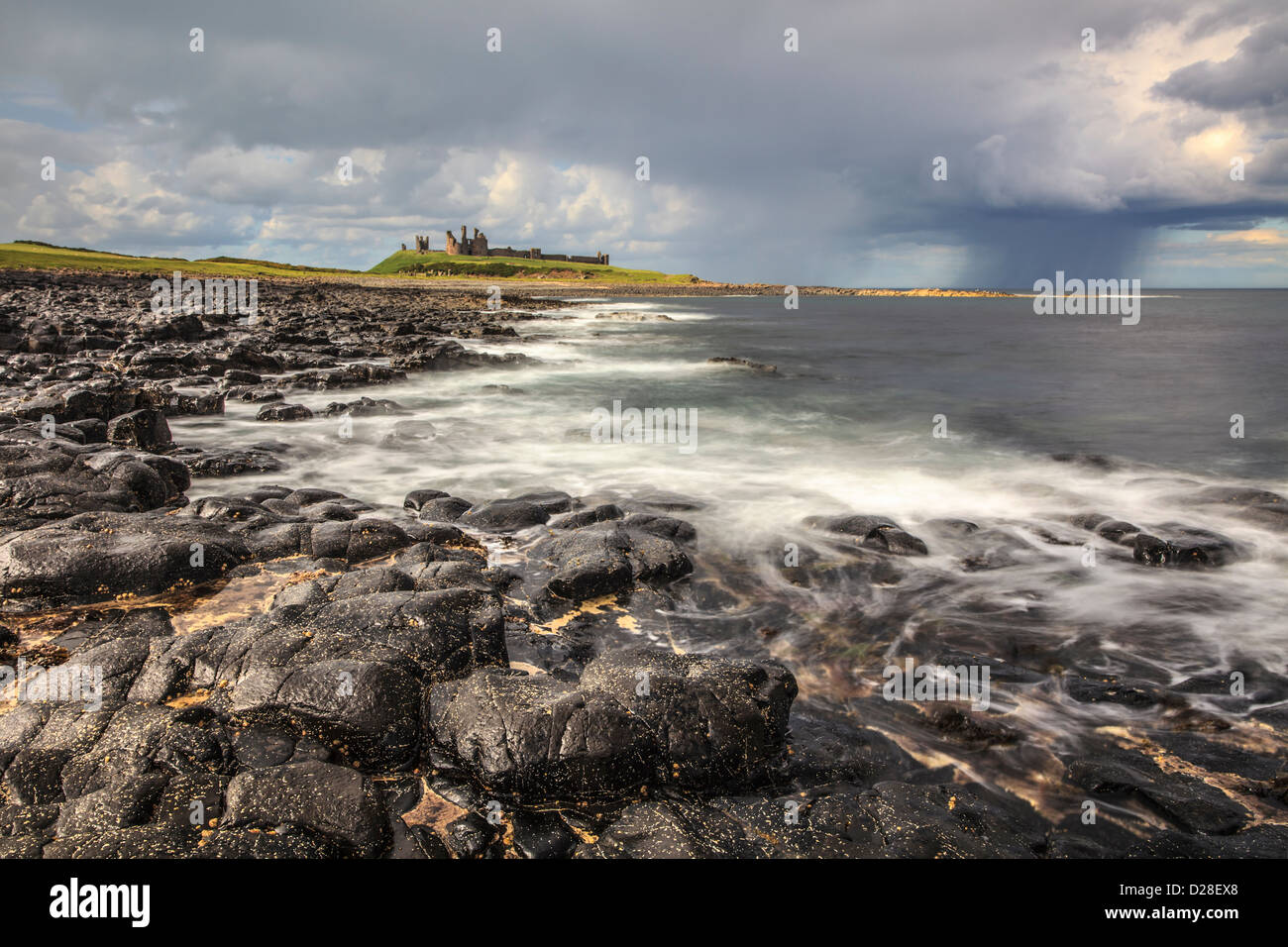 Dunstanburgh Castle captured from rocks beneath the coast path between ...