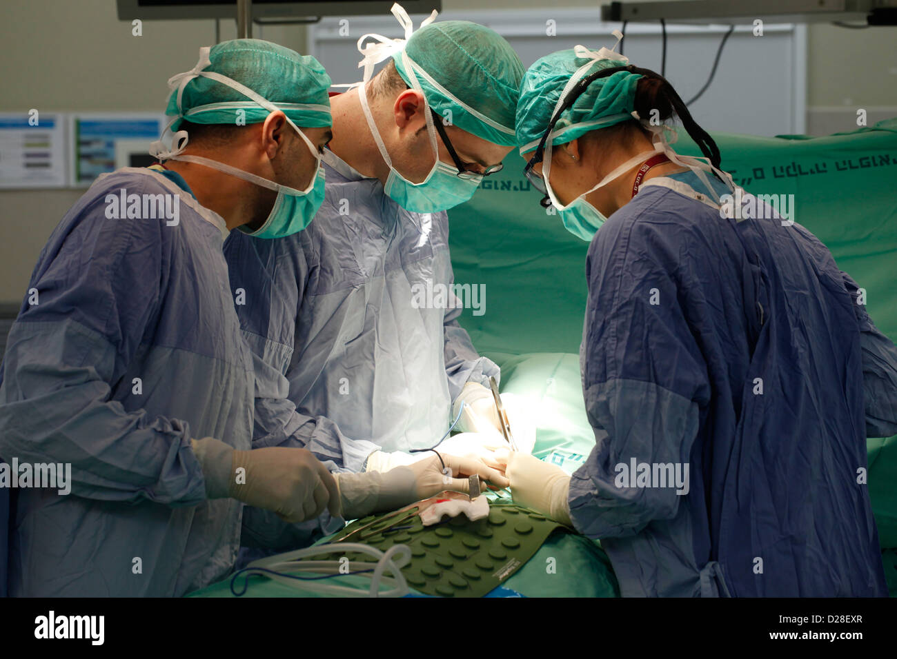 Surgeons wearing surgical mask performing operation in operating room ...