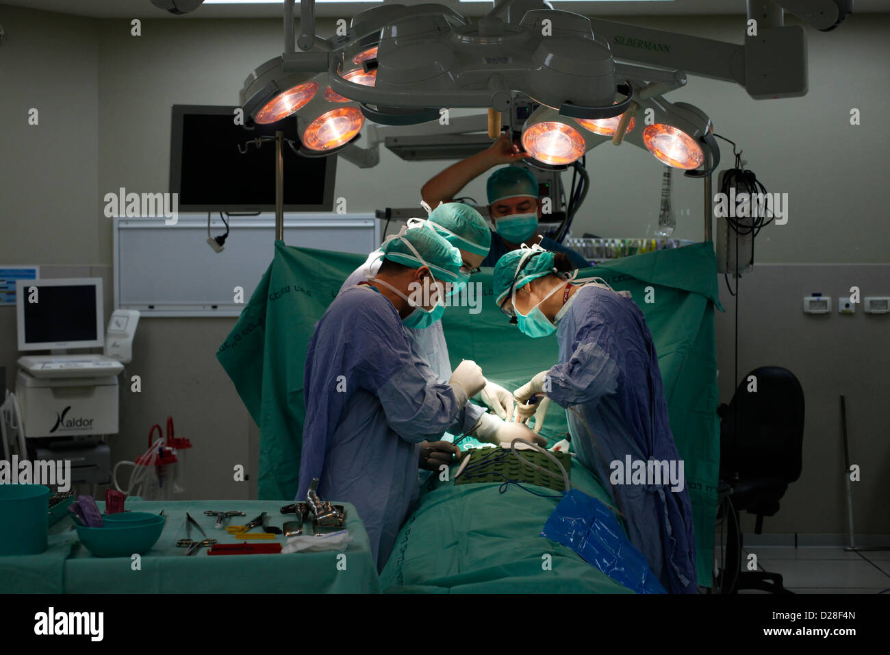 Surgeons wearing face mask performing operation in operating room in ...