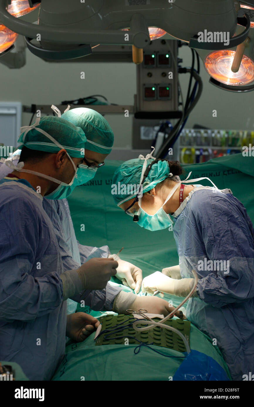 Surgeons wearing surgical mask performing operation in operating room ...