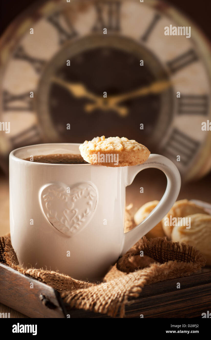 Coffee break time with focus on biscuit on top of mug Stock Photo - Alamy