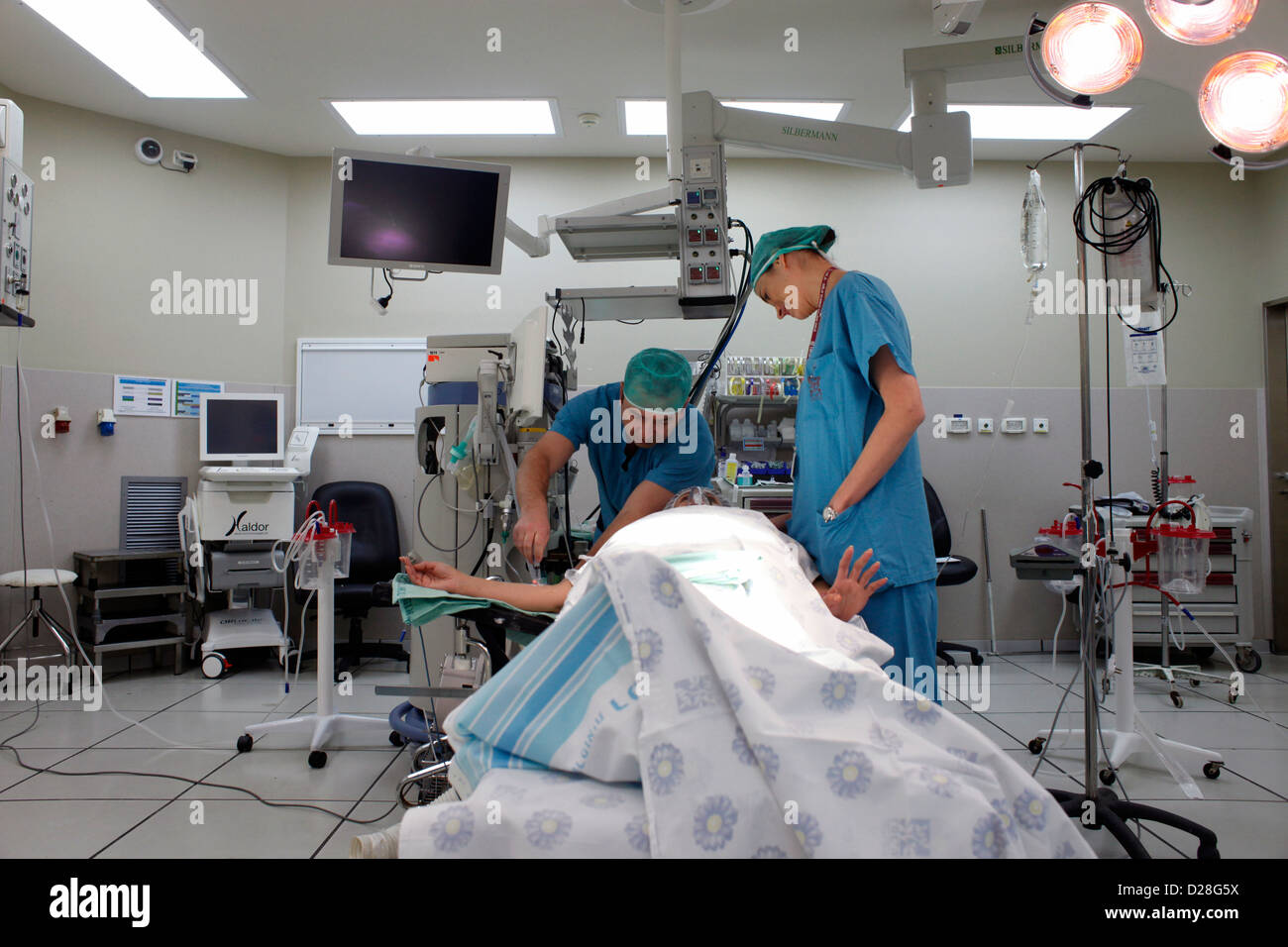 Anesthesiologist preparing a patient for operation in operating room in ...