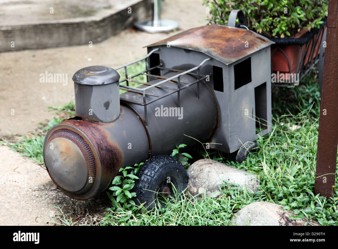It's a photo of a small rusted train in a garden. It's a iron sculpture ...