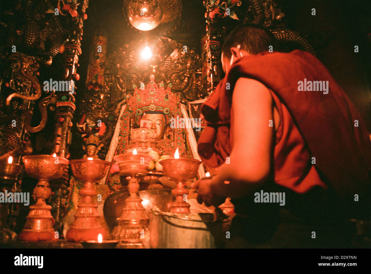 Tibet. Monk Lighting Candles At Shrine Stock Photo - Alamy